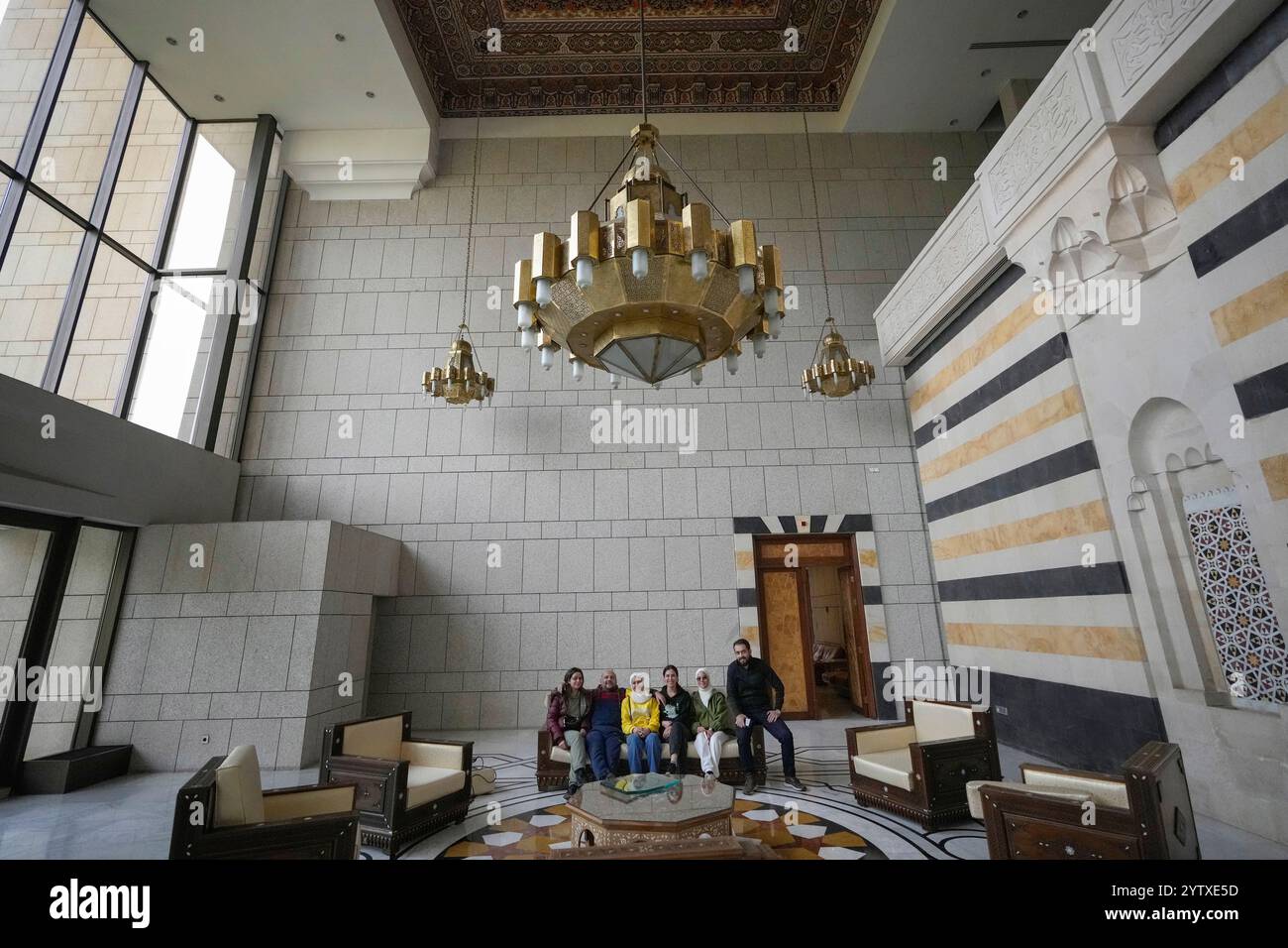 A group of Syrians pose for a family photo sitting on a couch in a hall ...