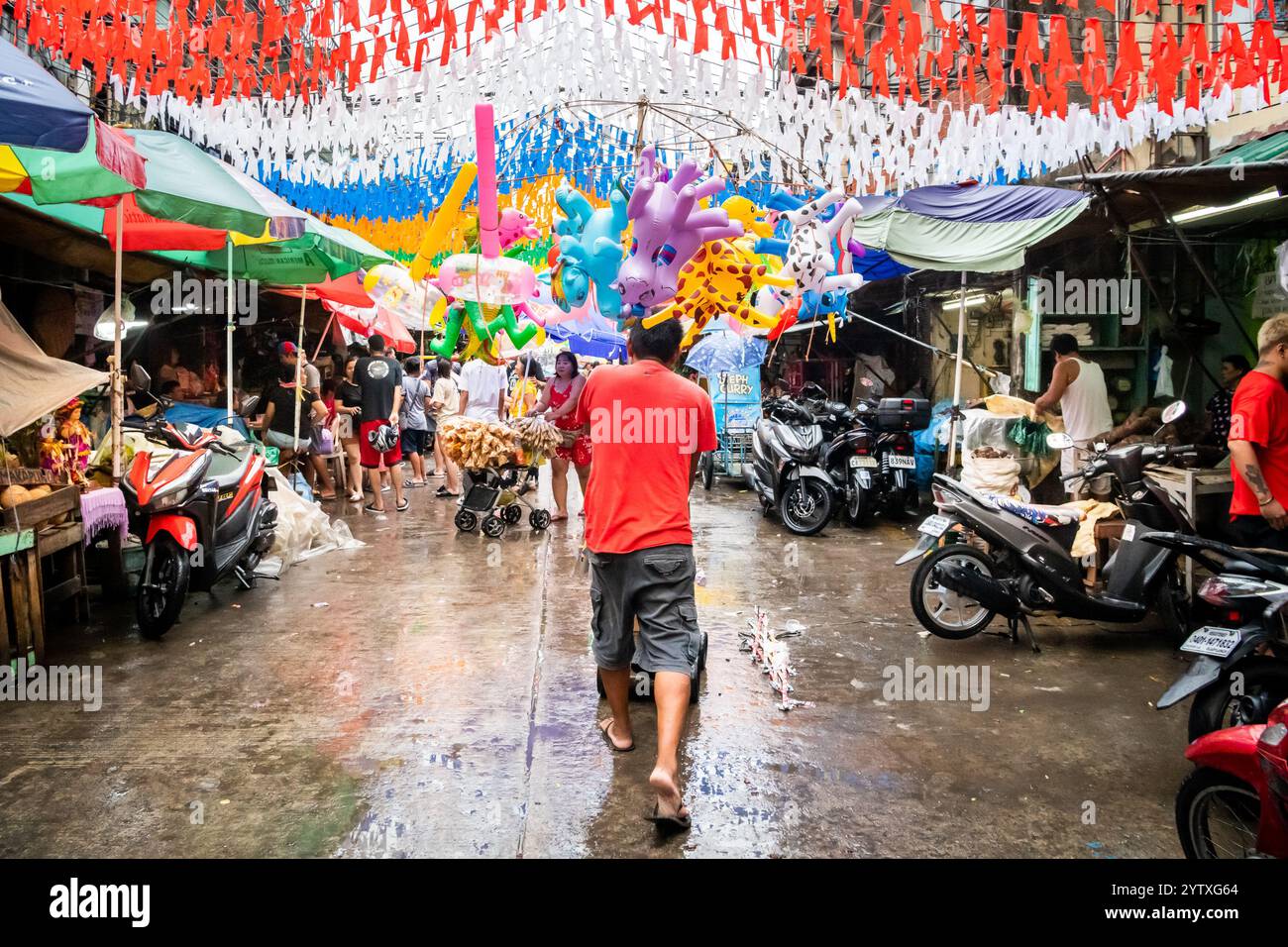 A street balloon vendor makes his way through the crowded streets of ...