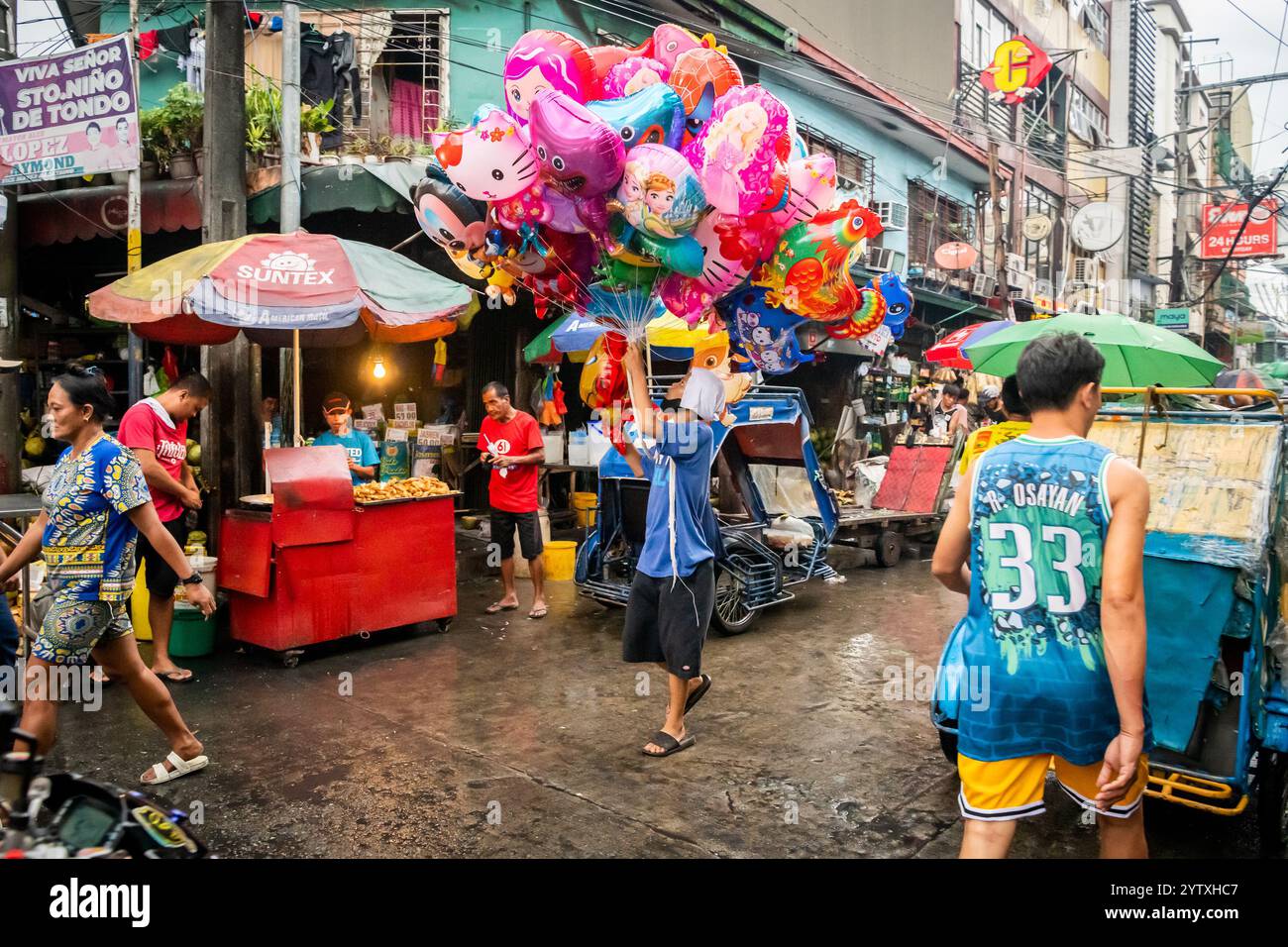 A street balloon vendor makes his way through the crowded streets of ...