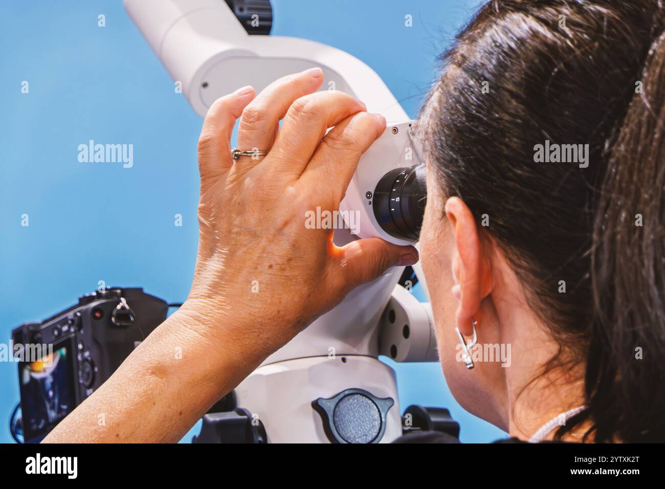 A woman looks into the binoculars of a dental microscope Stock Photo ...