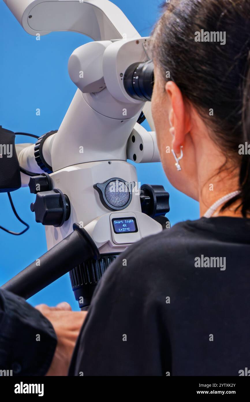 A woman looks into the binoculars of a dental microscope Stock Photo ...