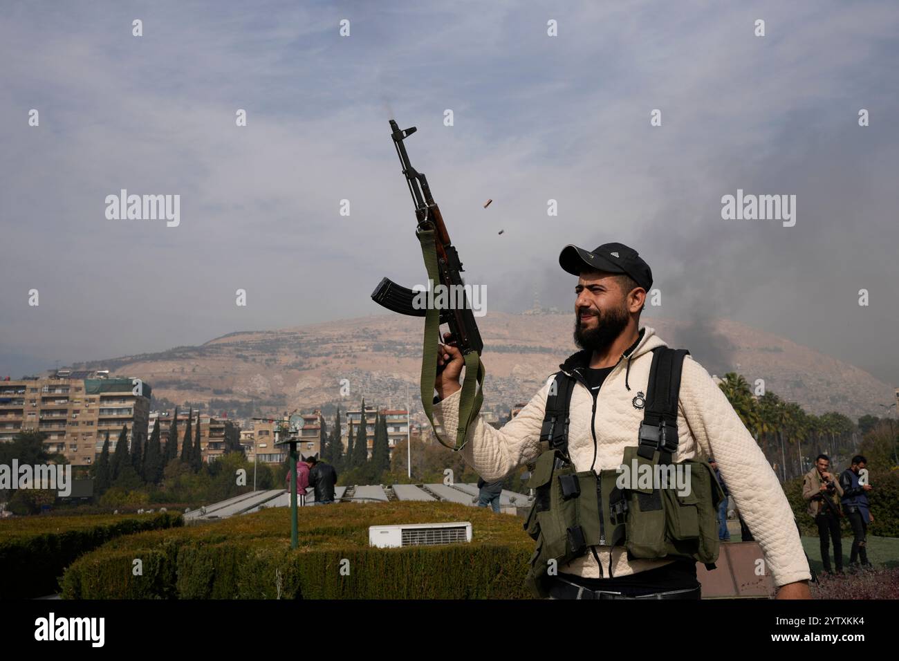 An opposition fighter fires on his AK-47, as he celebrates the take ...
