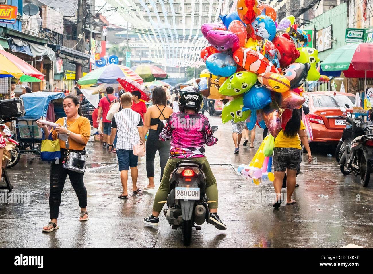A street balloon vendor makes his way through the crowded streets of ...