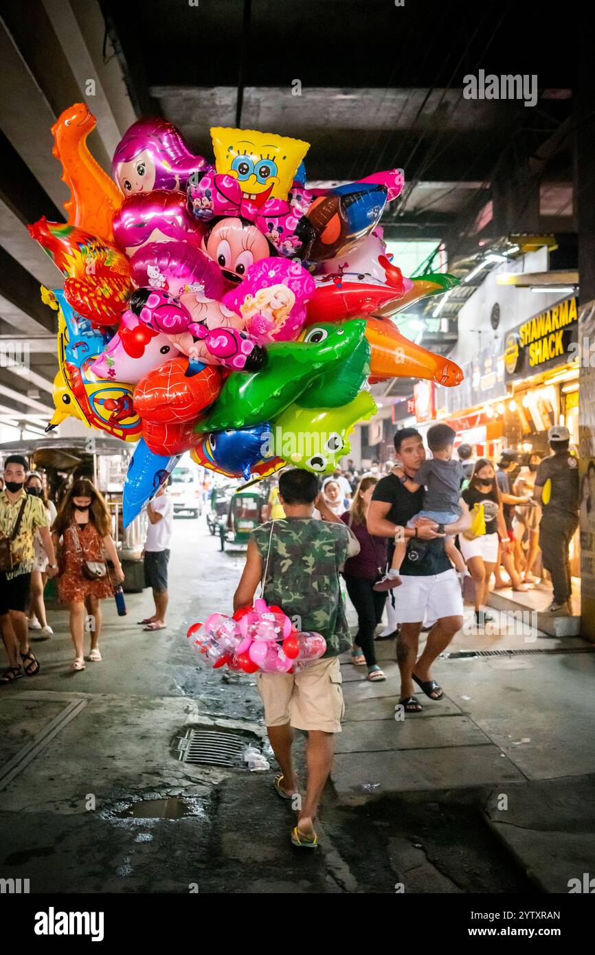 A street balloon vendor makes his way through the streets and walkway ...