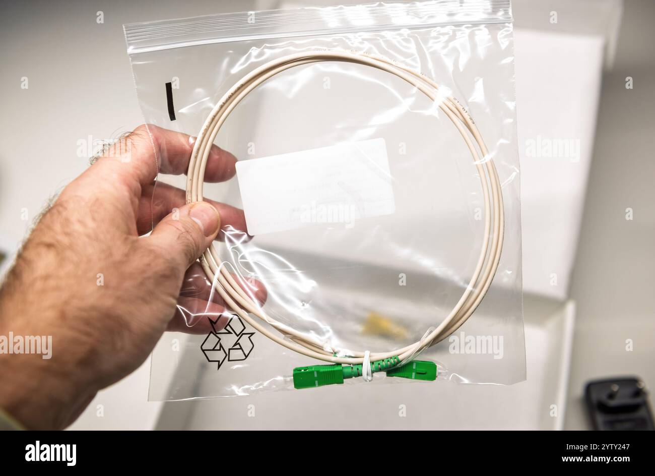 Hand holding a fiber optic cable sealed in a transparent plastic bag ...
