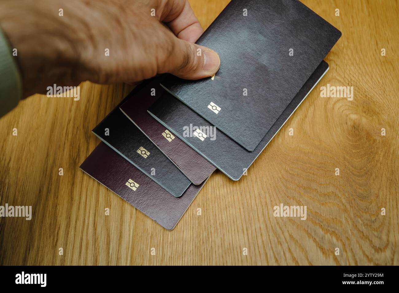 Hand arranging a stack of passports on a light wooden table, showing ...