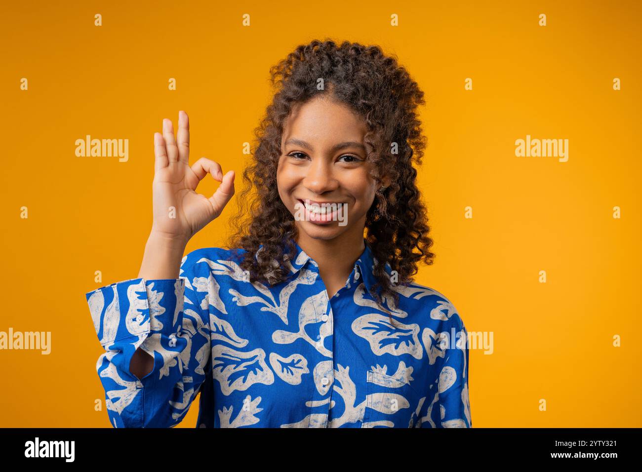 Positive teenager girl with hand sign Ok, Okay gesture.Lady on yellow ...