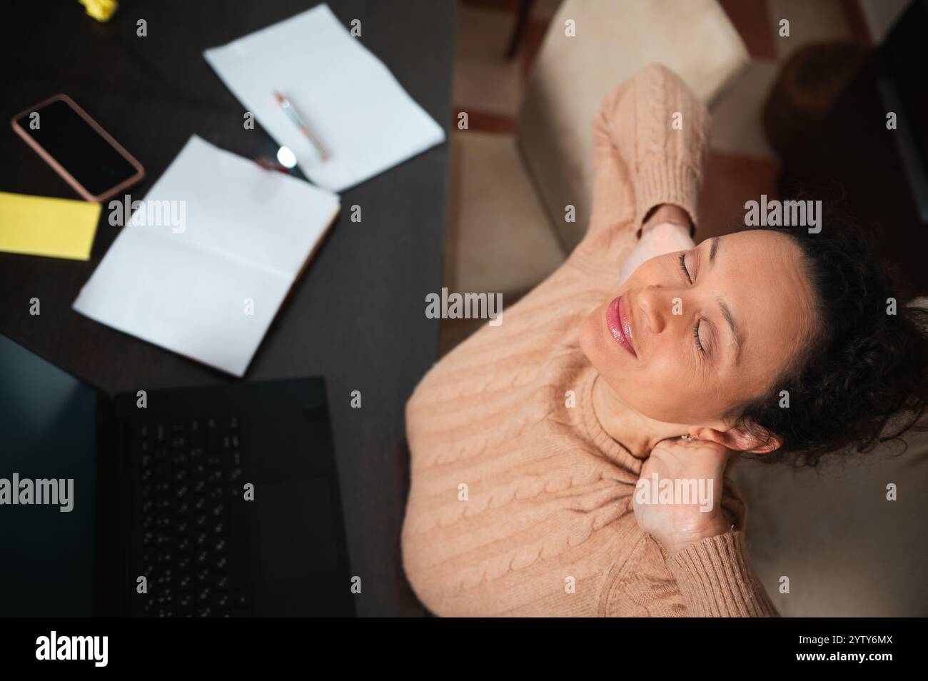 A woman enjoys a relaxing break at her desk, with a serene expression ...