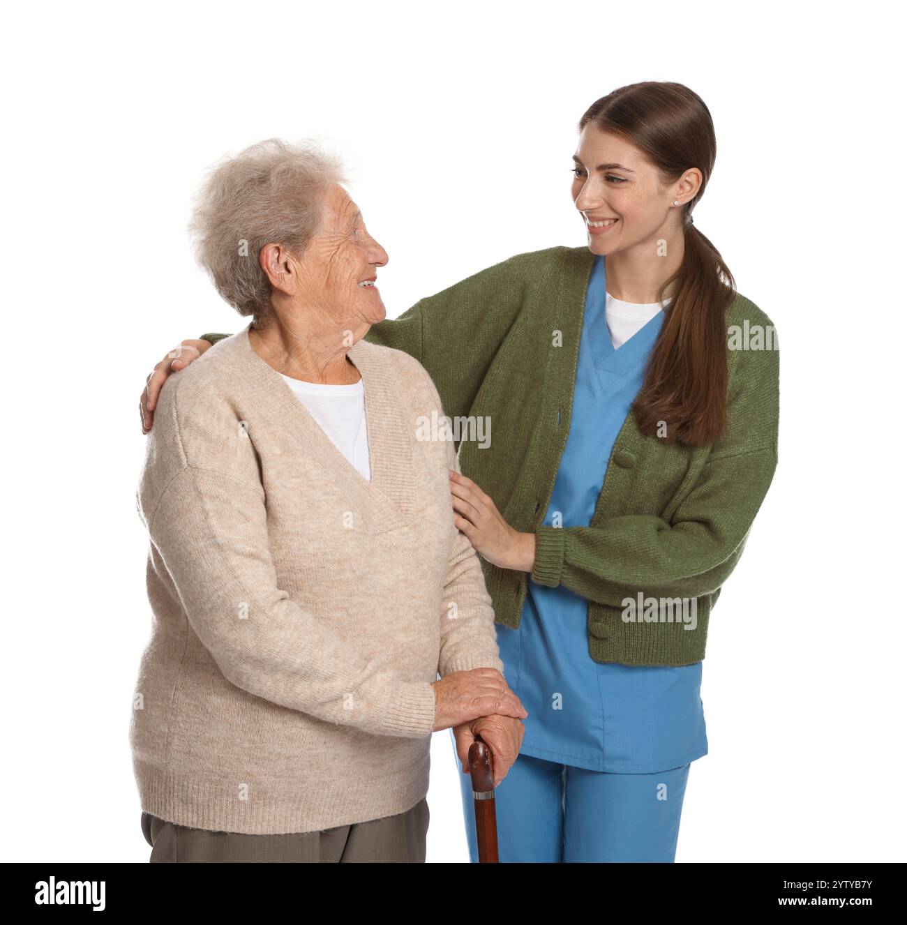 Caregiver supporting senior woman with walking cane on white background ...