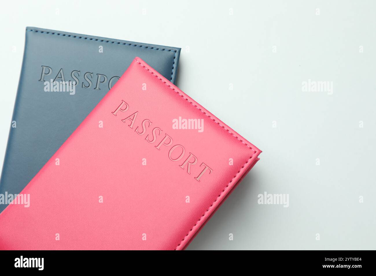 Passports in color covers on light background, top view. Space for text ...