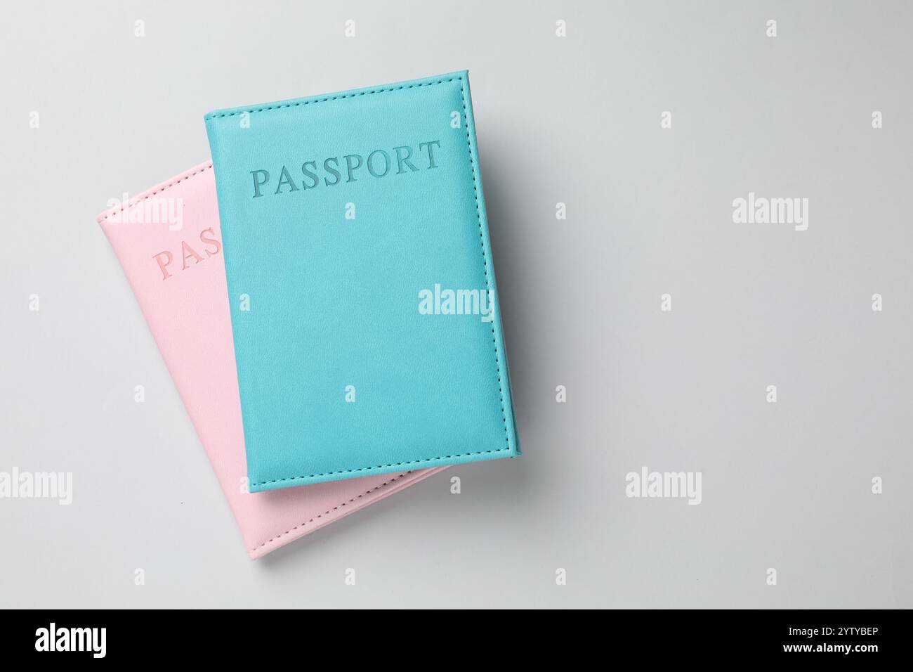 Passports in color covers on light background, top view. Space for text ...