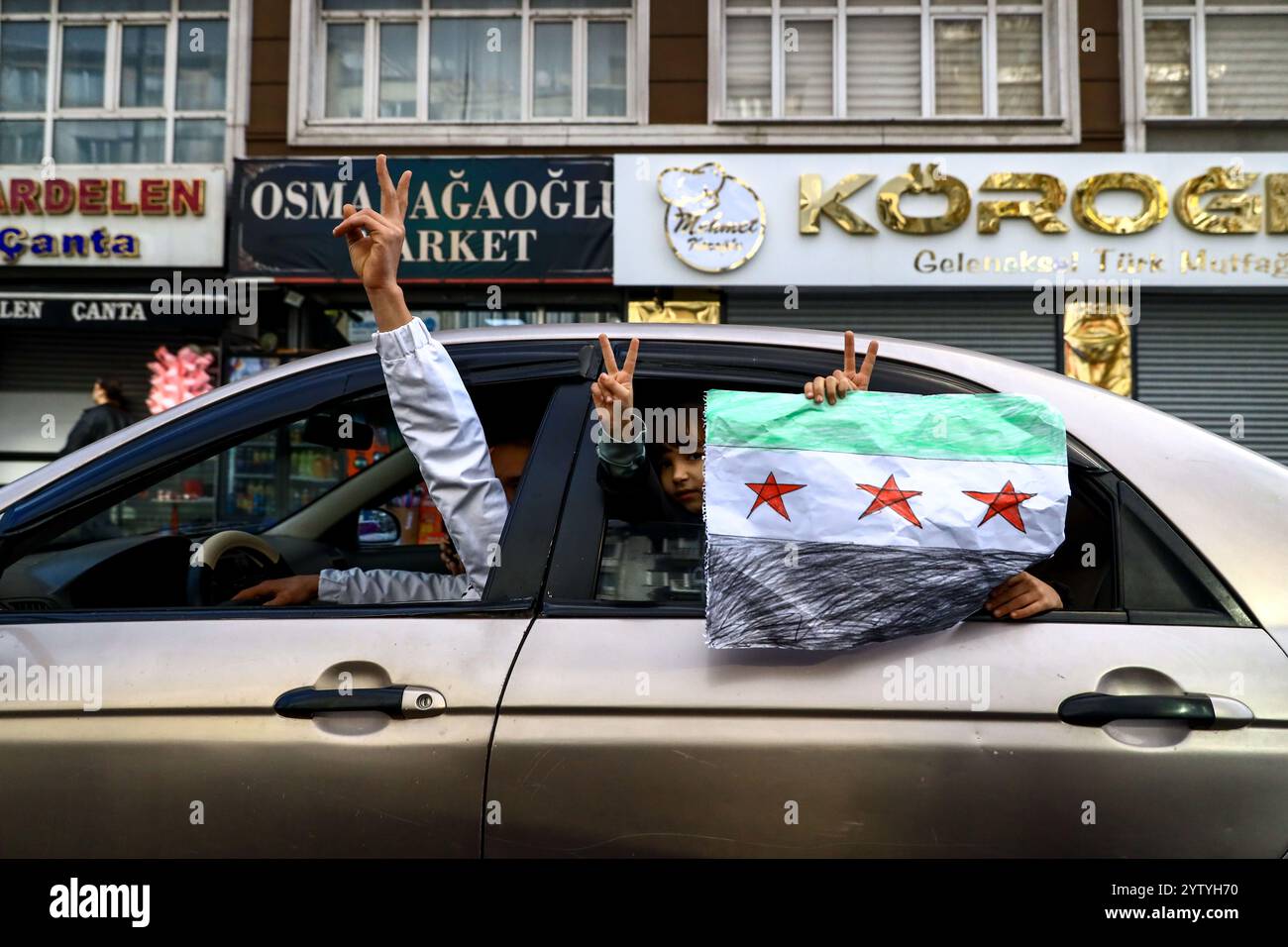 A child waves the Syrian flag from inside a car in the streets of ...