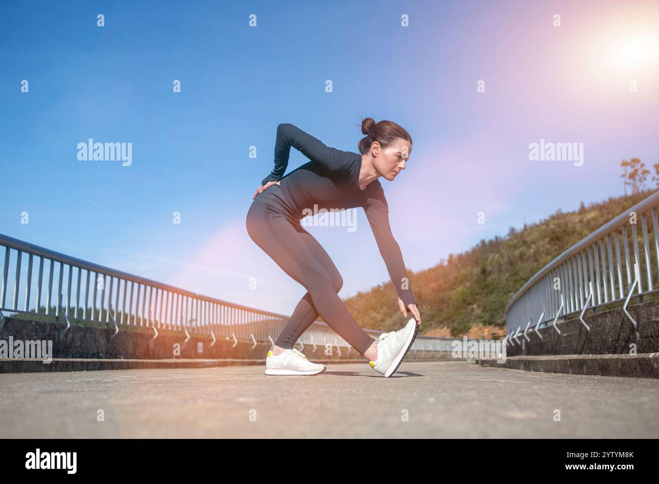 Sporty woman runner doing a leg stretch exercise to help with back pain ...