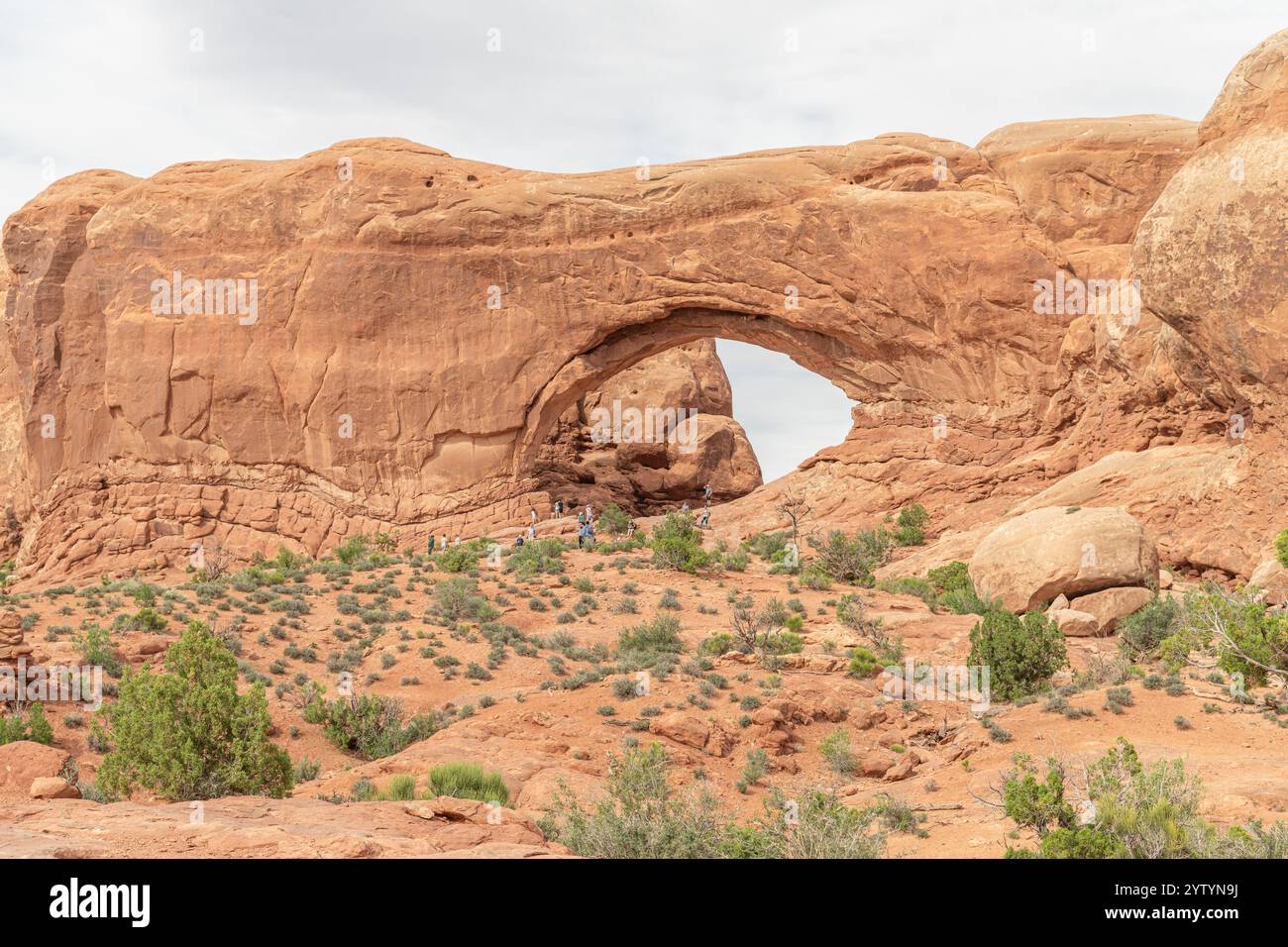 Tourists exploring the North Window Arch in Arches National Park, Utah ...