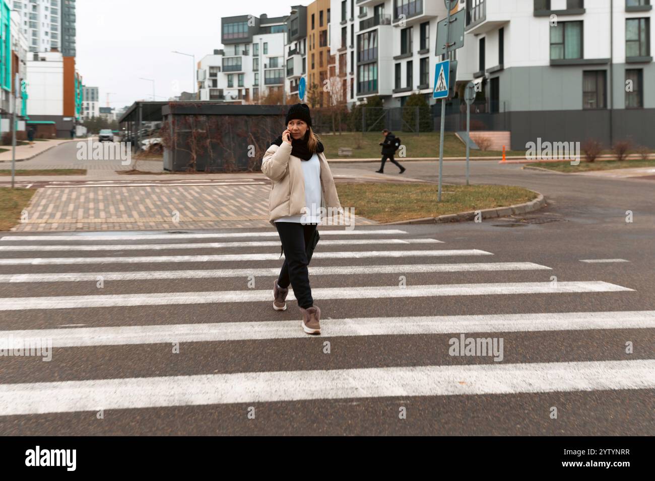 Person crossing a pedestrian walkway in a modern urban neighborhood ...