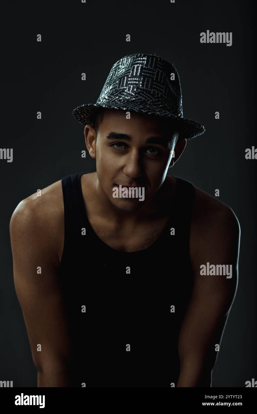 Young man wearing a stylish hat, striking a pose for a dance photoshoot ...