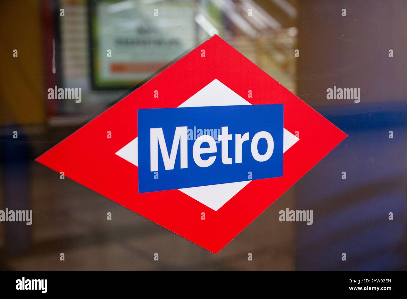 A red and blue Metro sign is on a window. The sign is diamond shaped ...