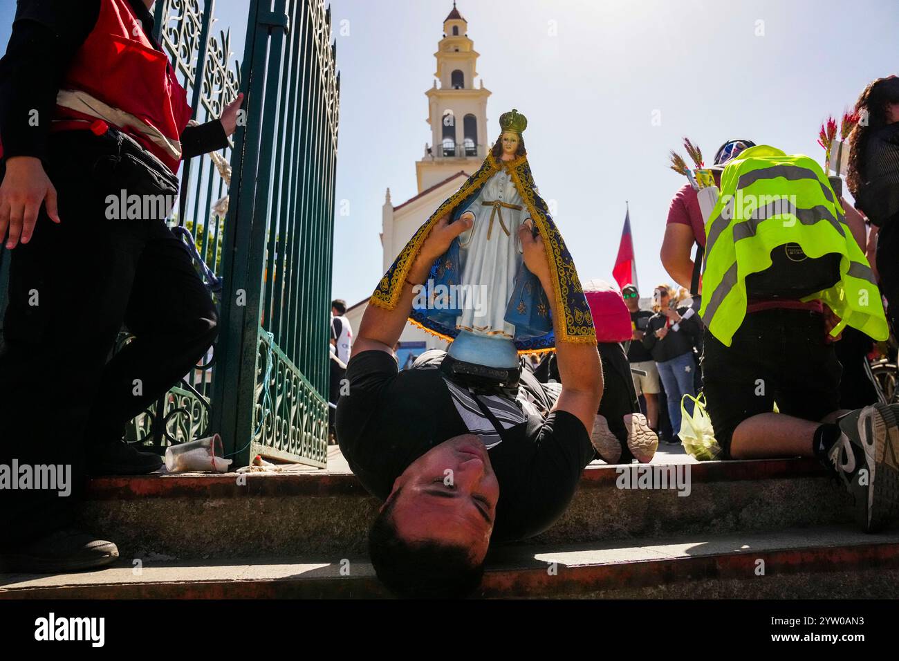 A pilgrim holds an effigy of the Virgin Mary as he crawls out of the Lo ...