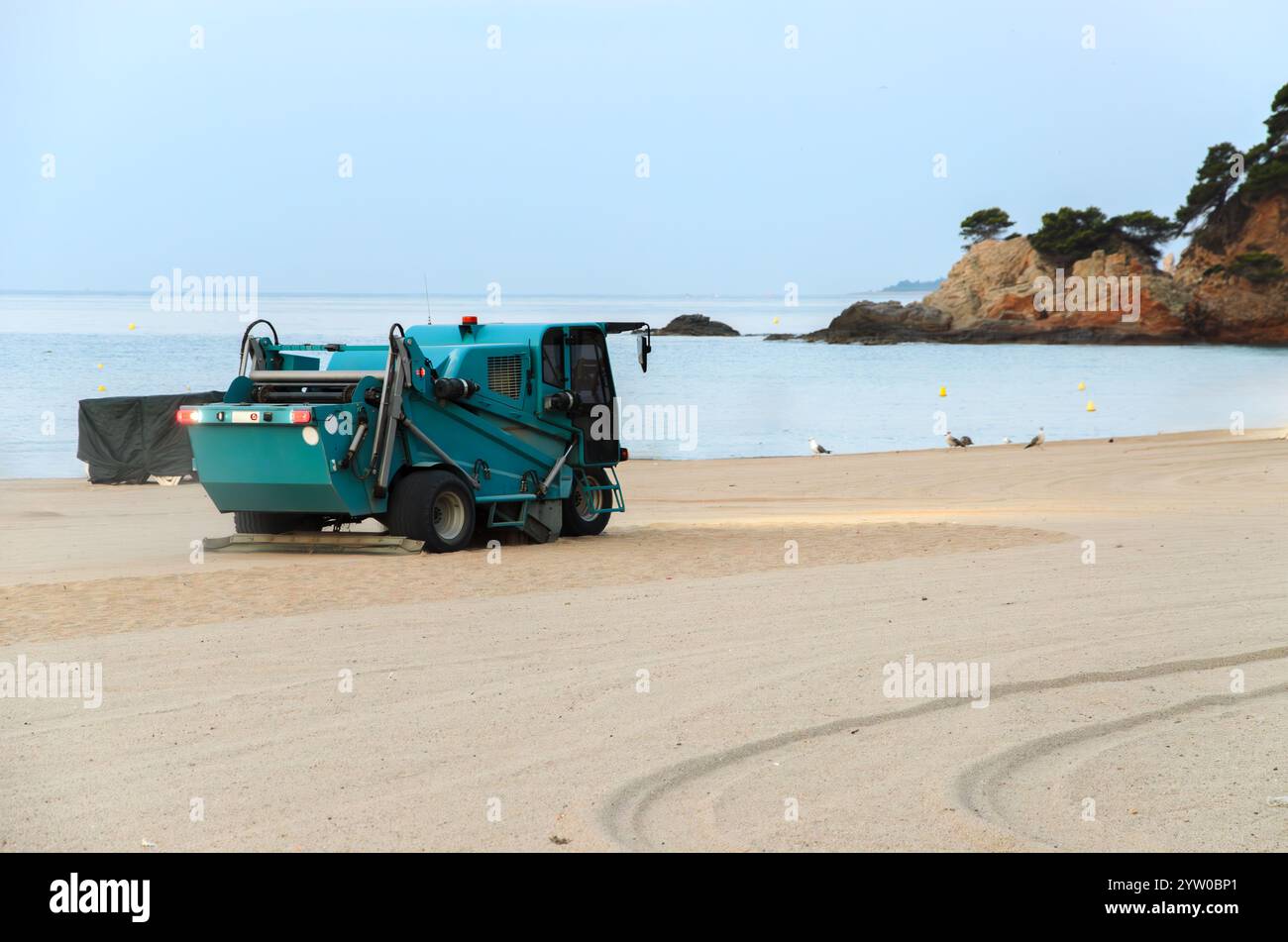 A beach cleaning machine clears debris from the sand, ensuring a ...