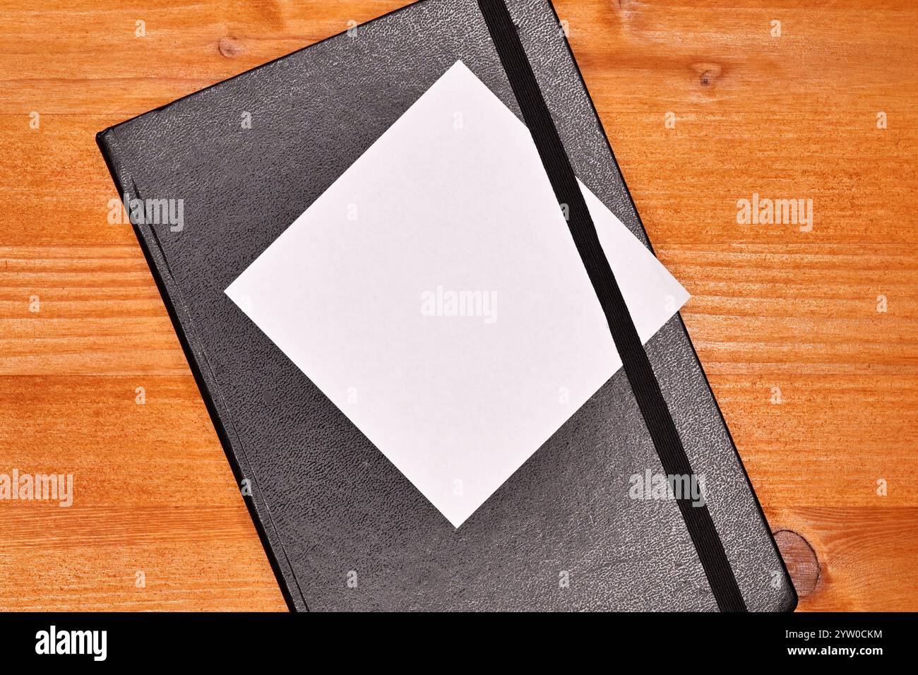 Blank white square shaped note paper on notebook as mockup copy space ...
