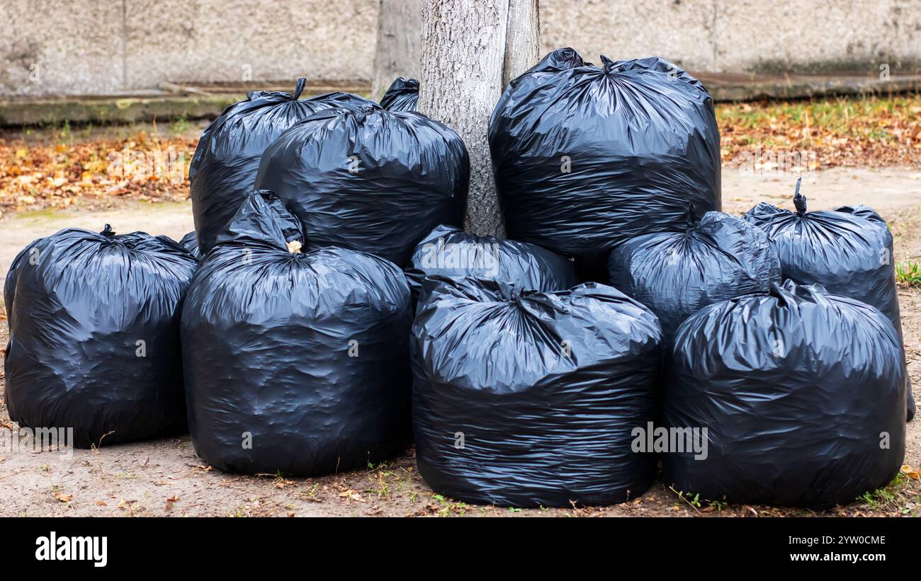 A large pile of black garbage bags is sitting right in front of a tall ...