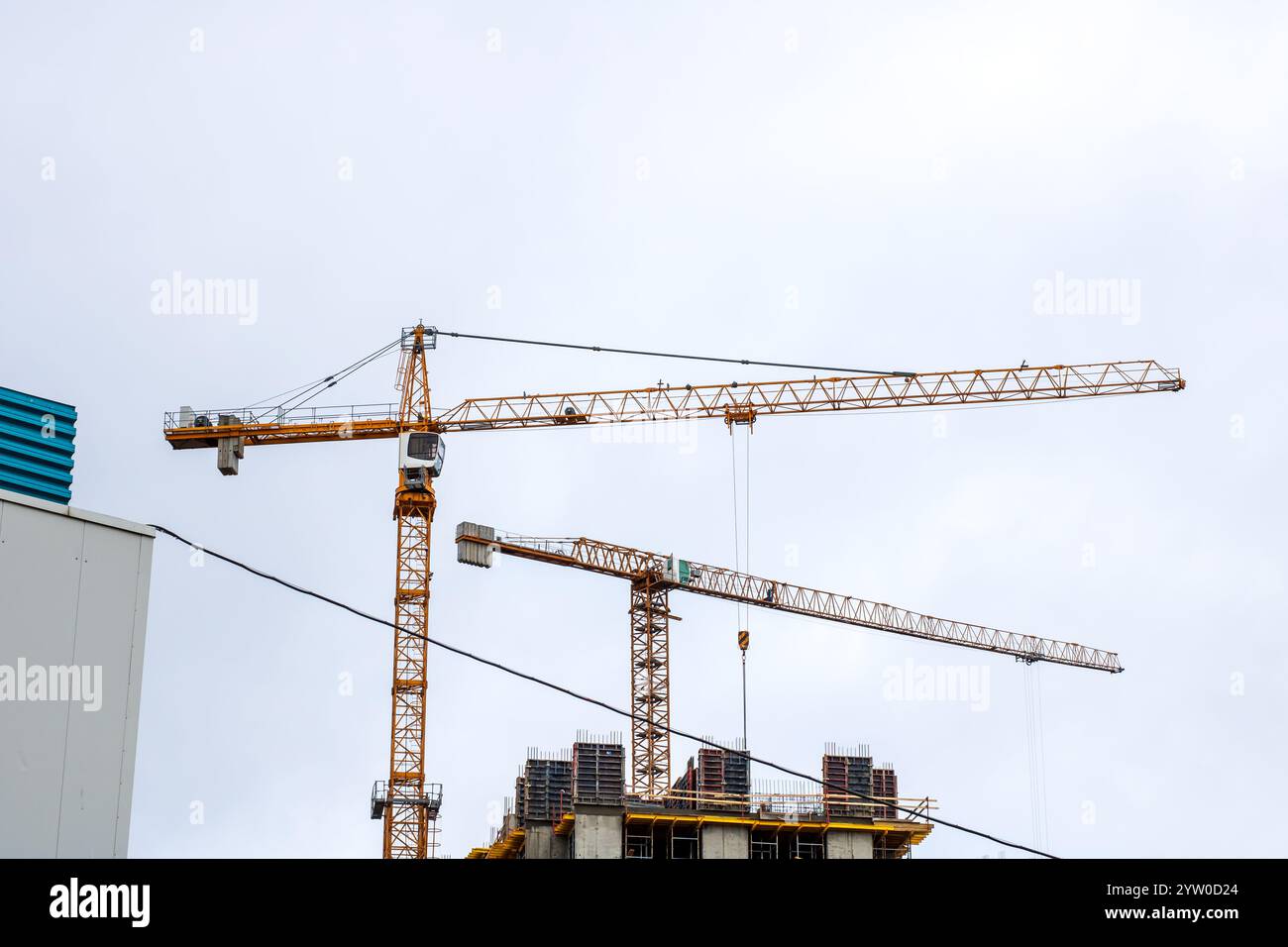 A bustling construction site featuring cranes towering above, with a ...
