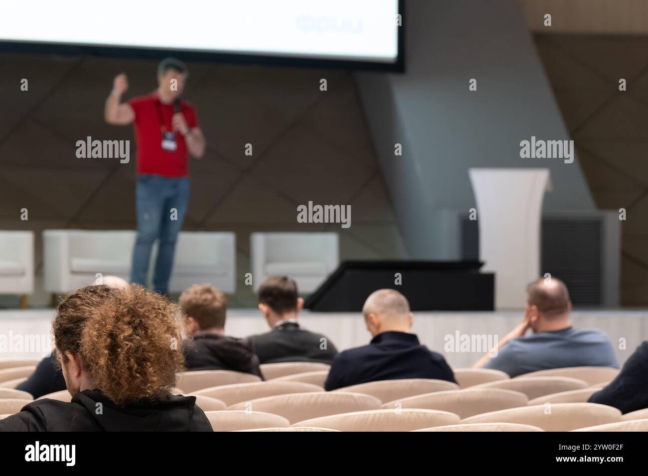 Conference scene showing speaker on stage addressing attentive audience ...