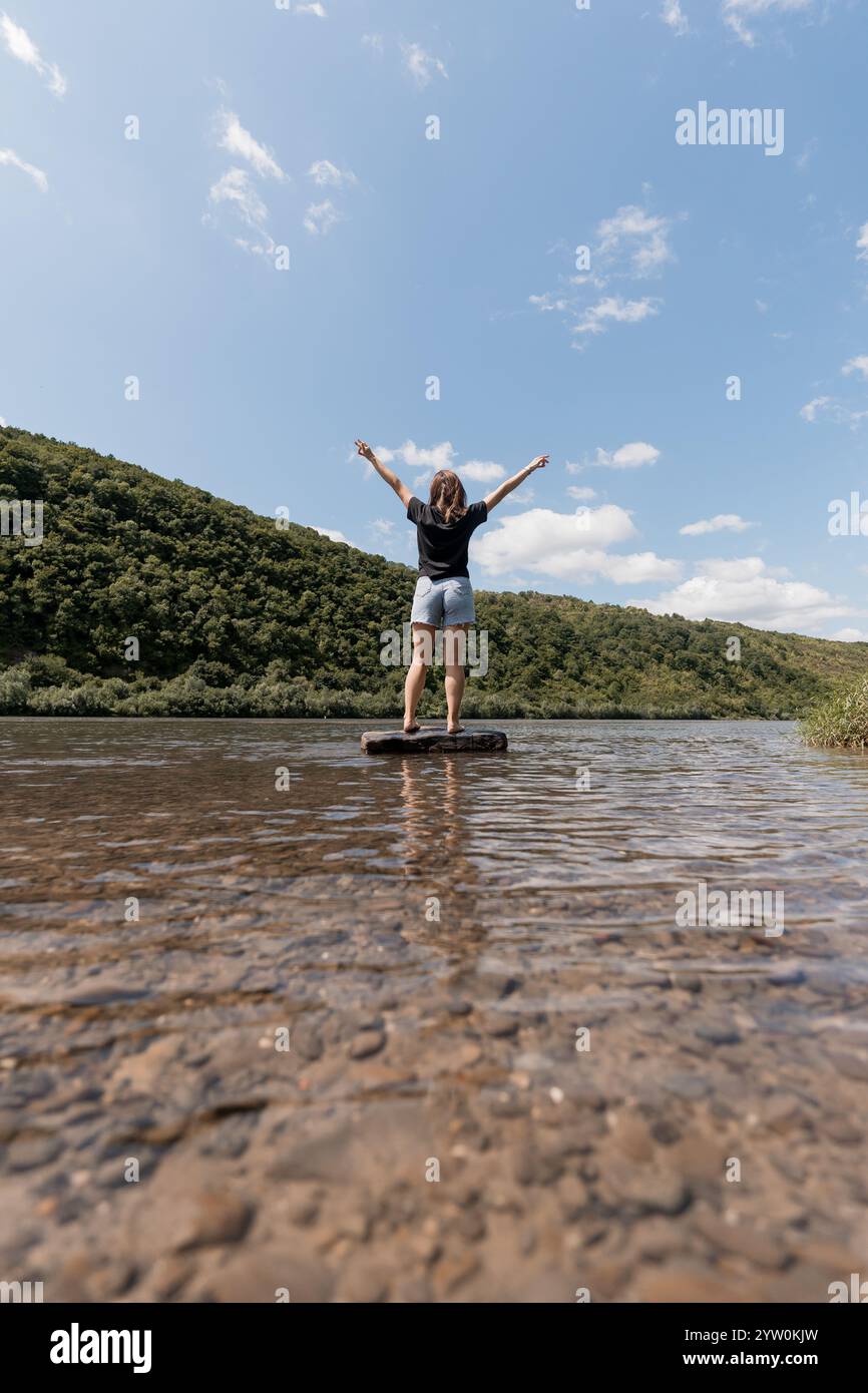 Joyful Freedom at the Riverbank Under a Bright Blue Sky Stock Photo - Alamy