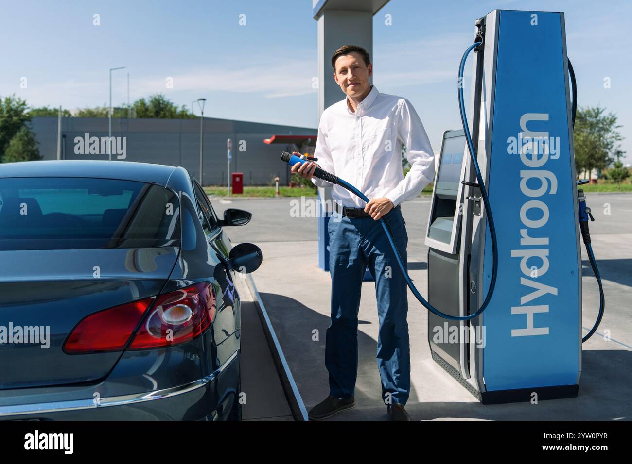 Man holds a hydrogen fueling nozzle on a hydrogen filling station. Refueling car with hydrogen ...
