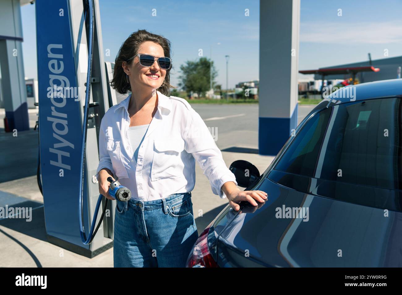 Woman holds a hydrogen fueling nozzle on a hydrogen filling station ...