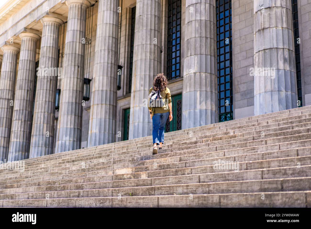 Confident mid-adult student walking up university steps Stock Photo - Alamy