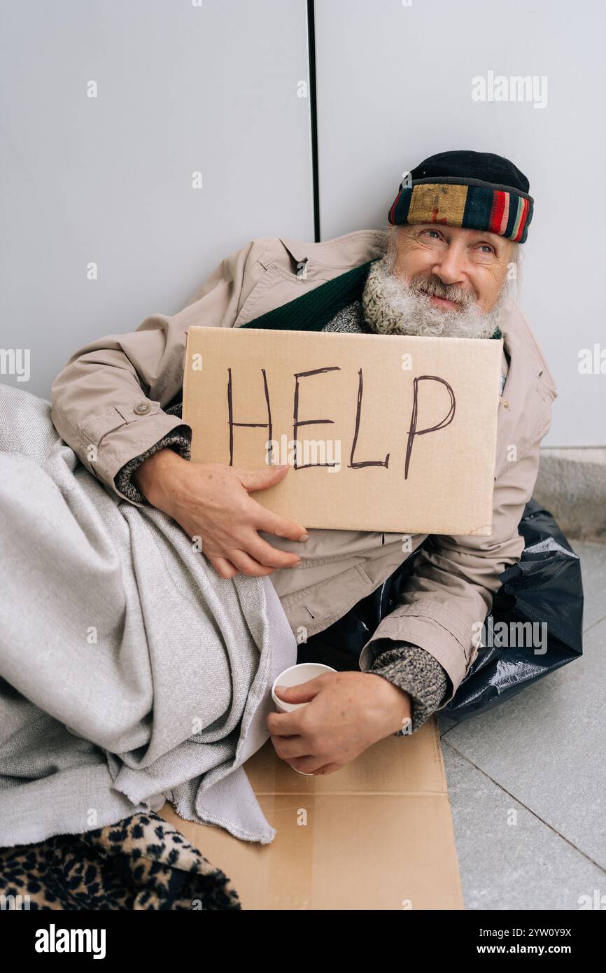 Vertical portrait of crying aged homeless man sitting on cold city ...