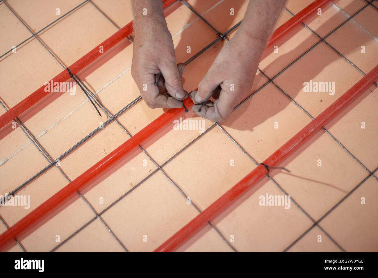 Installation of underfloor heating. A worker fastens pipes for ...