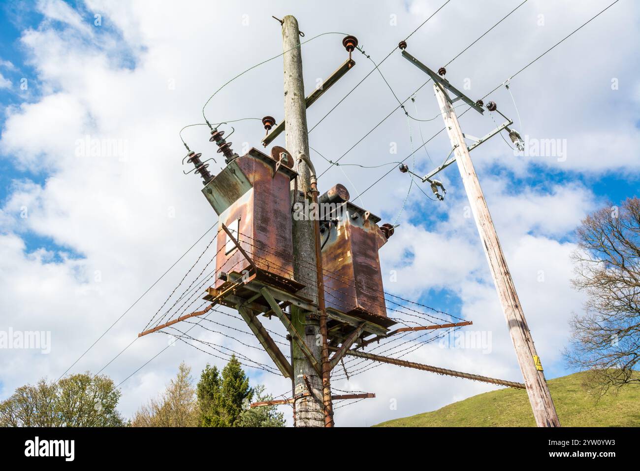 A pair of rusty old pole-mounted electrical transformers with ...
