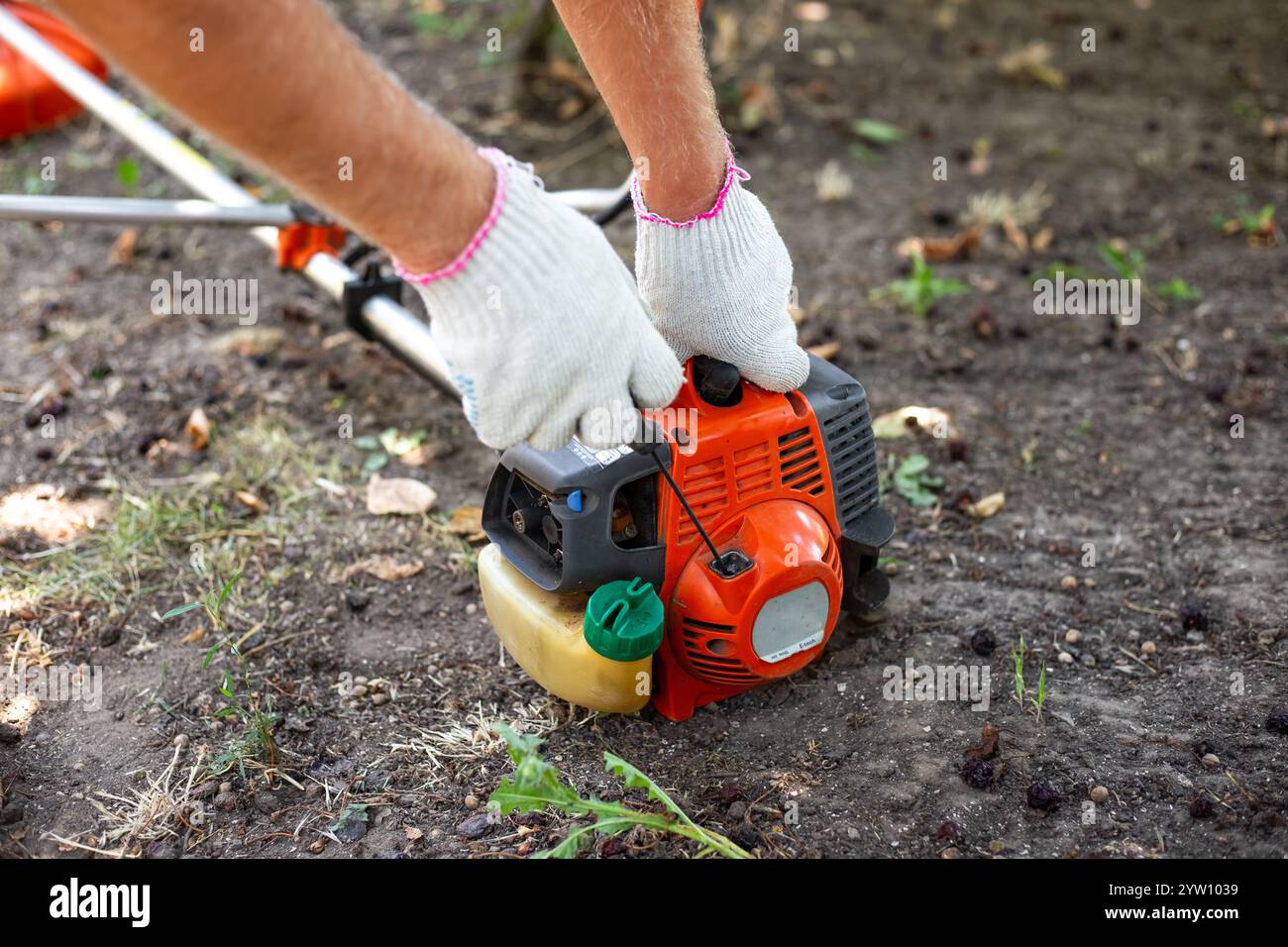 Starting a gas mower to mow grass. A man pulls the recoil starter to ...