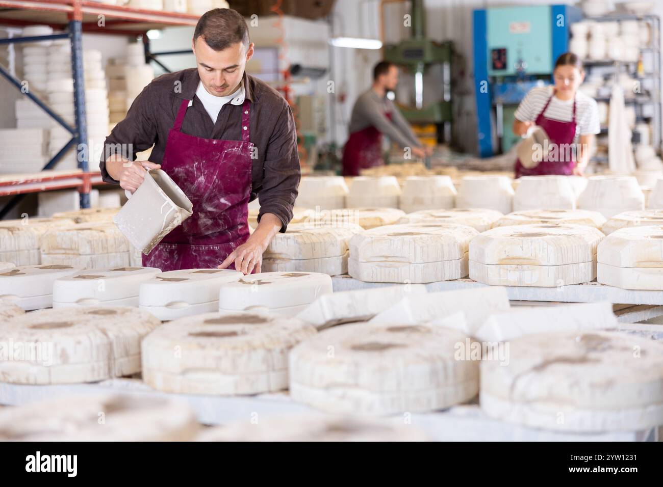 Artisan pouring slip into casting molds in pottery workshop Stock Photo ...