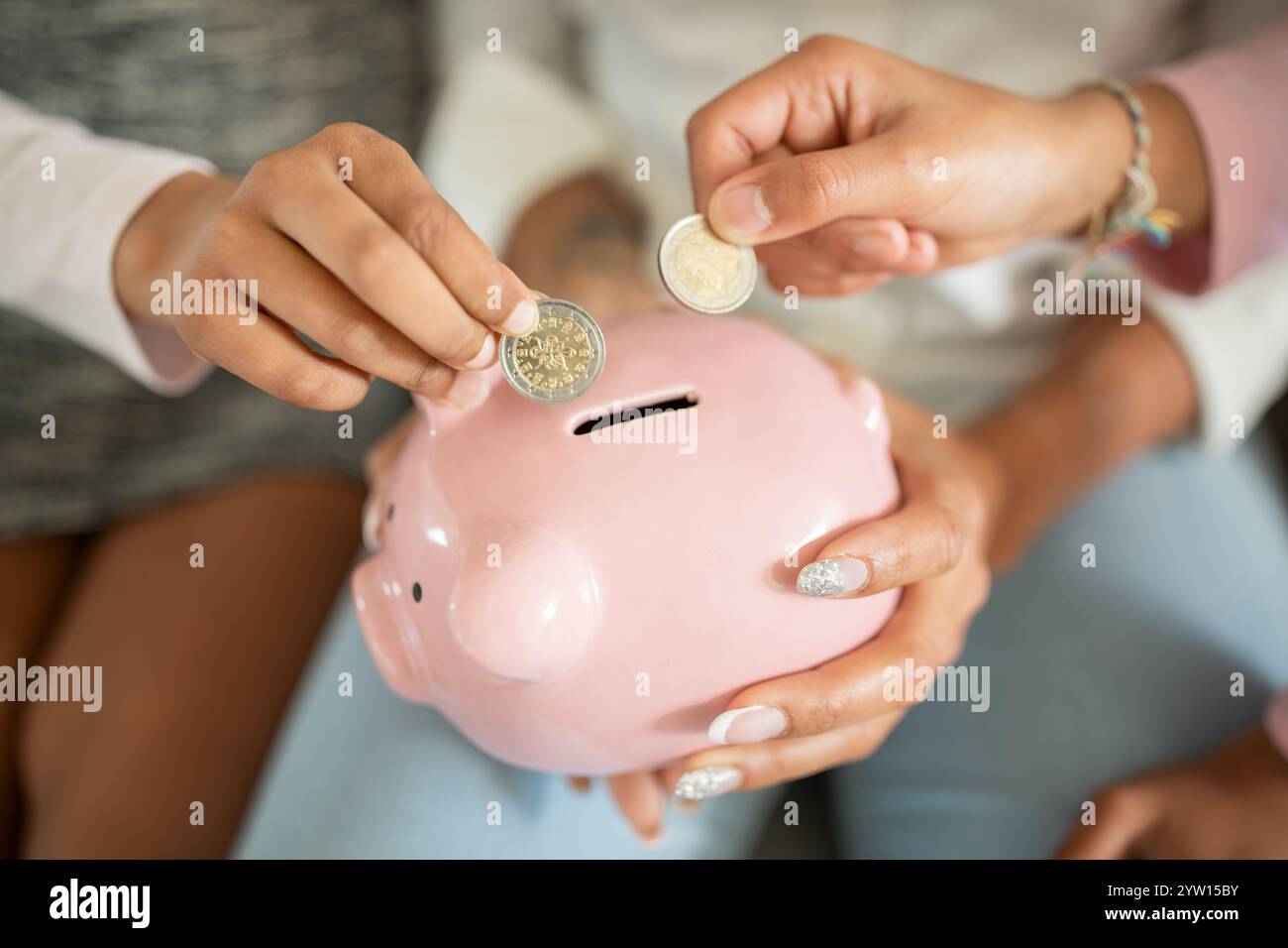 Family members teach children about saving money with a piggy bank ...