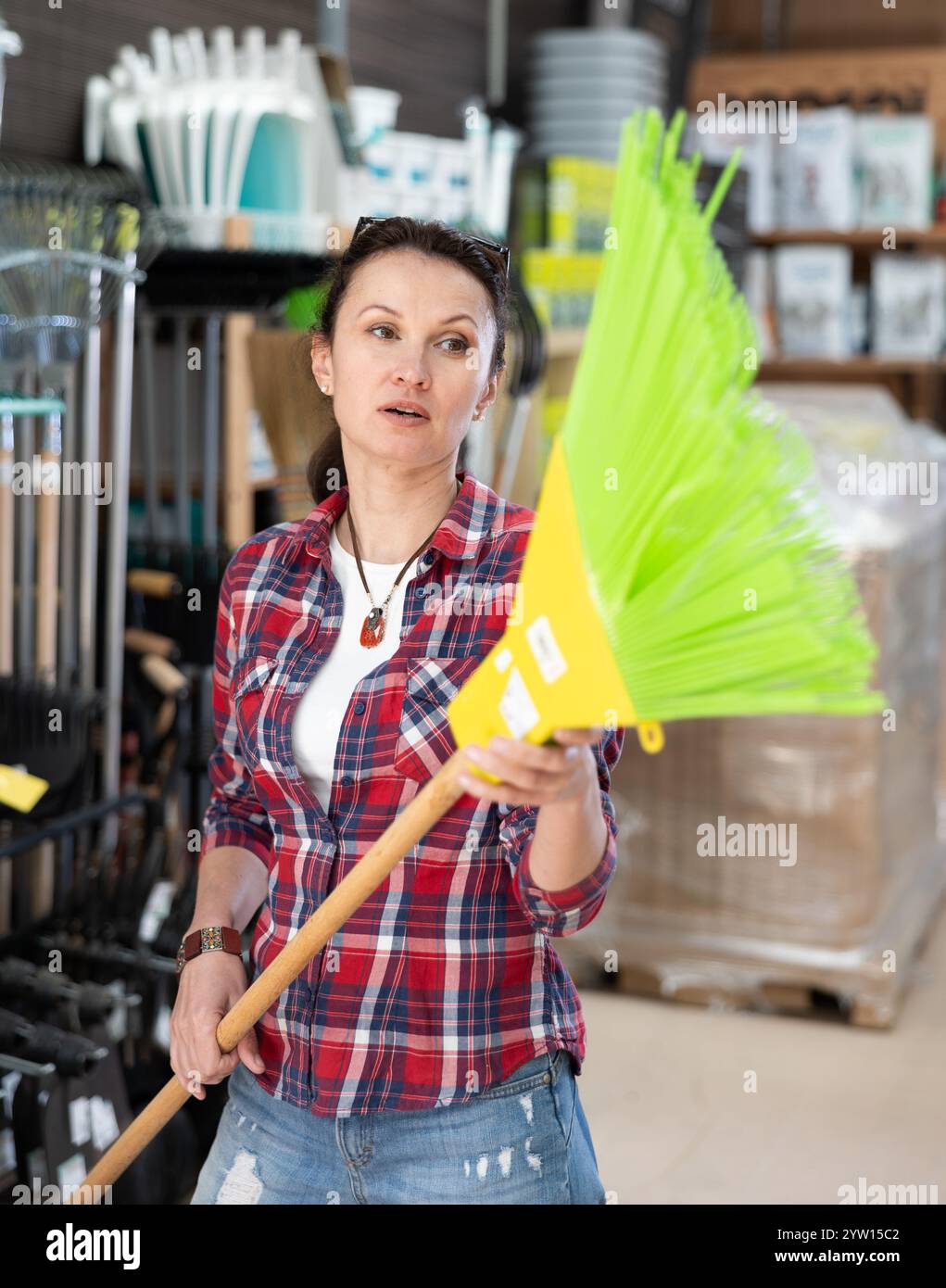 Woman shopping at hardware store - choosing broom Stock Photo - Alamy