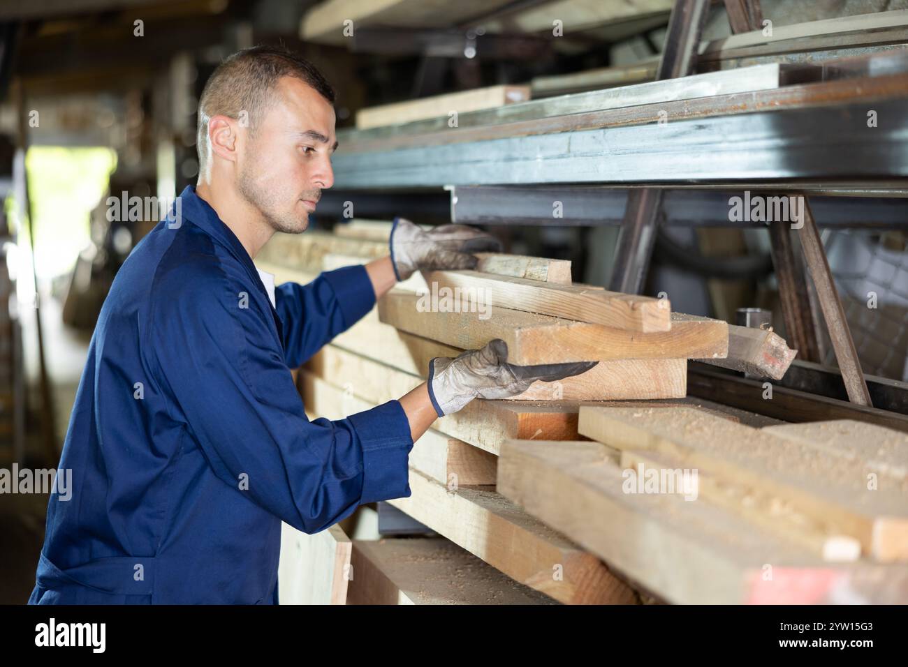 Male sawmill worker stores wooden boards in enterprise warehouse Stock ...