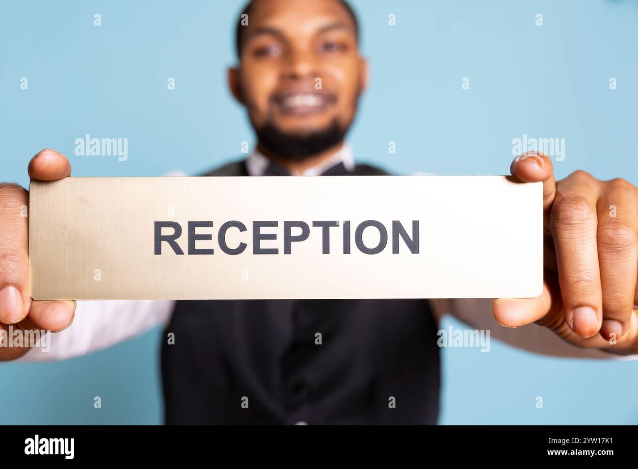 Young bellhop pointing at an indicator for the reception area front ...