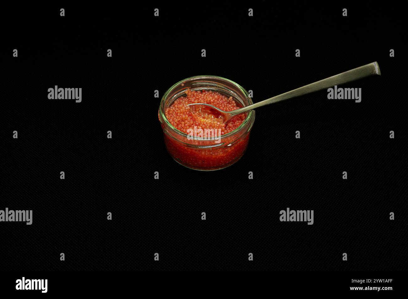 red lumpfish roe and a spoon in a glass jar isolated on black Stock ...