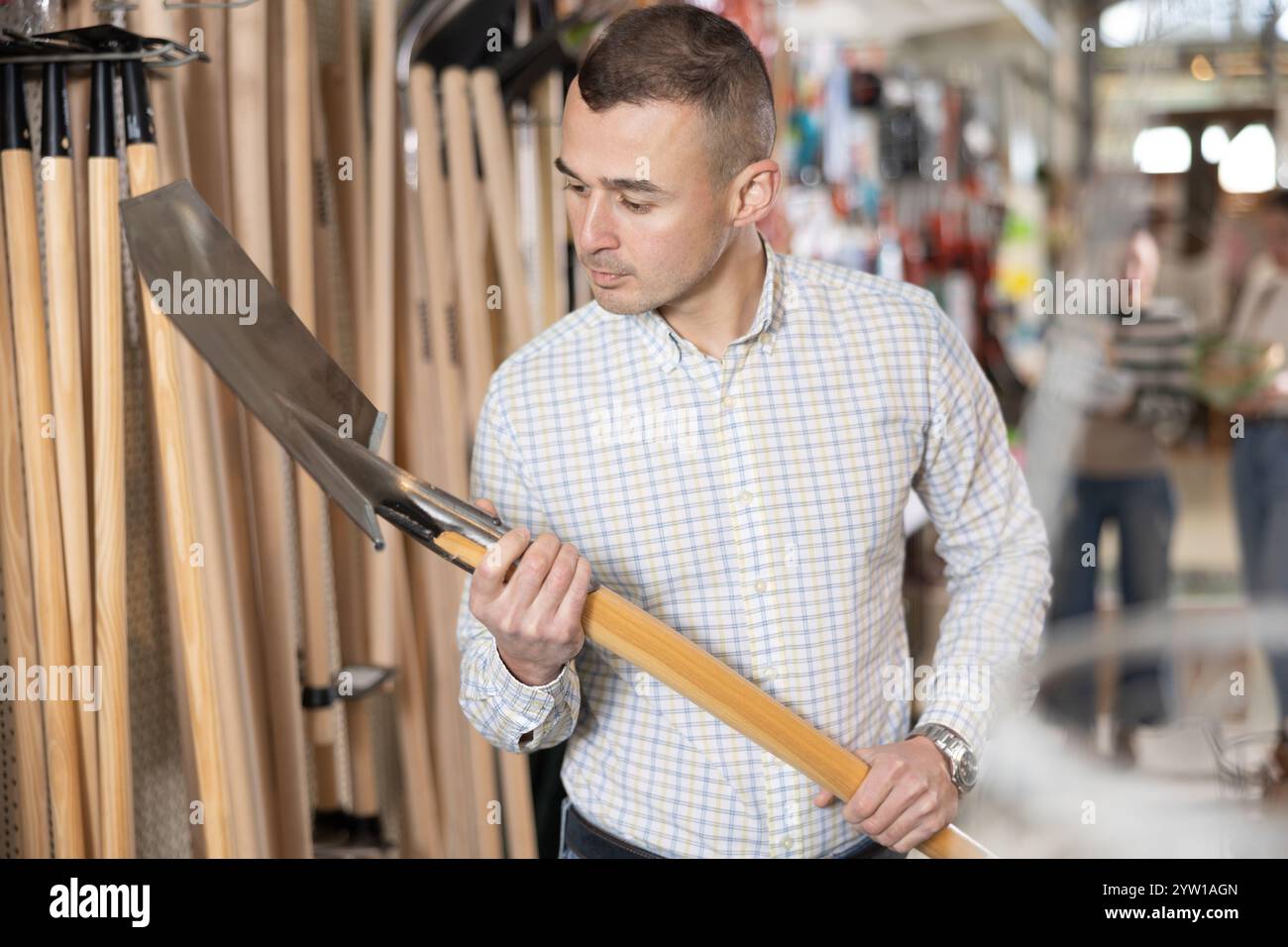 Buying shovel in supermarket - man with interest chooses shovel in ...