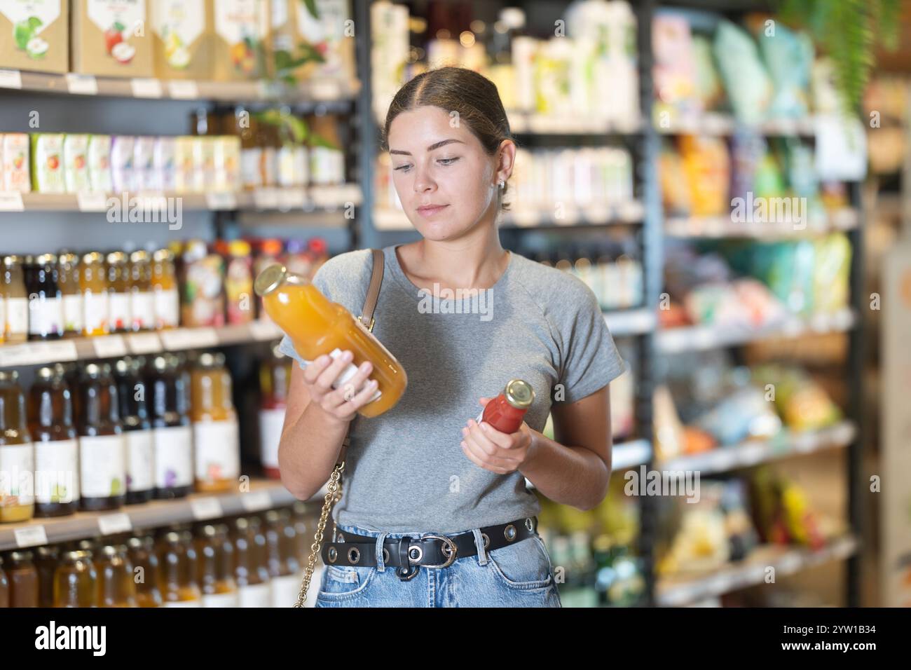 Female customer comparing two bottles of juice in grocery store Stock ...