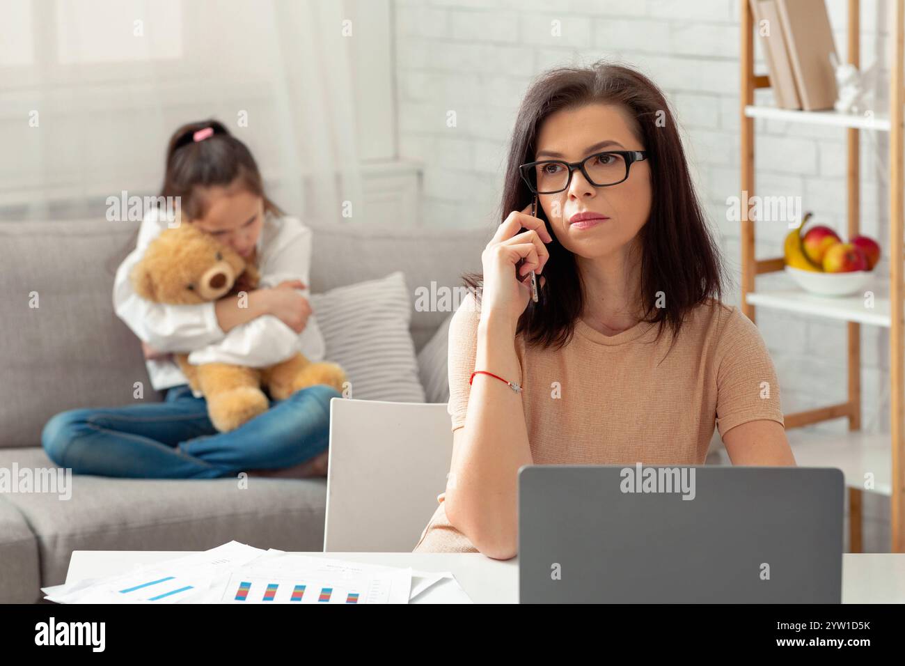 Modern working mom doing online job, her neglected daughter hugging ...