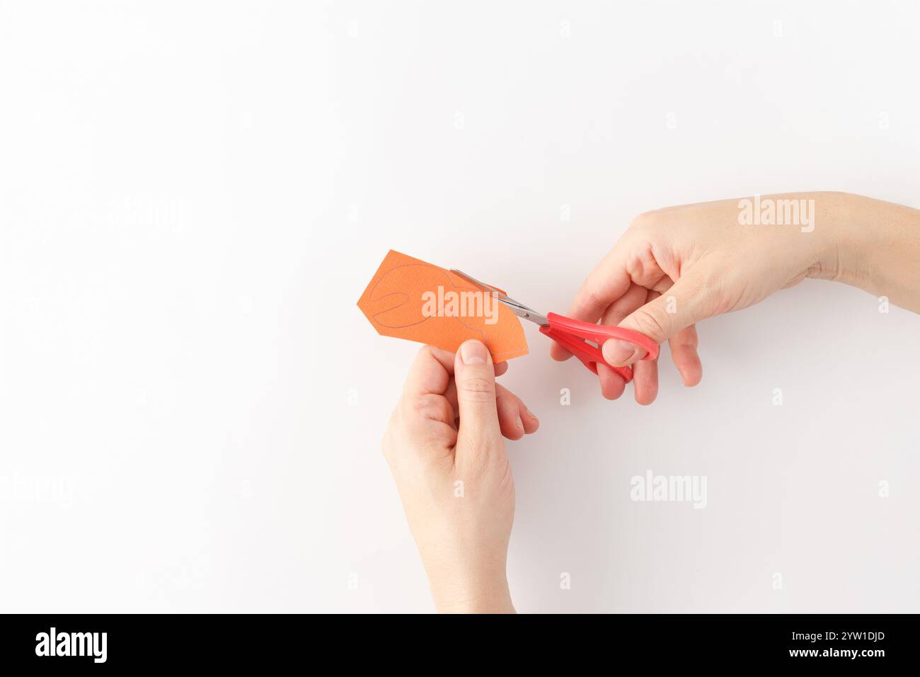 creative process in progress, Hands cutting orange paper into crab claw ...