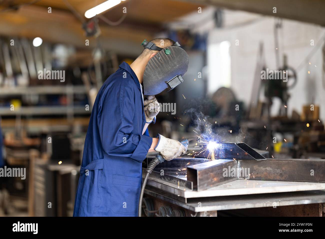 Male welder standing with a welding semi-automatic machine and a safety ...