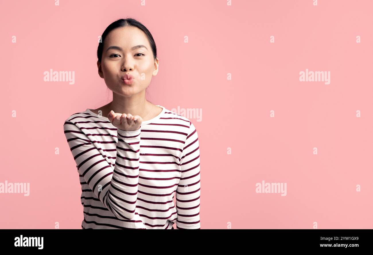 Young Cheerful Asian Woman Pouting Lips And Blowing Air Kiss At Camera ...