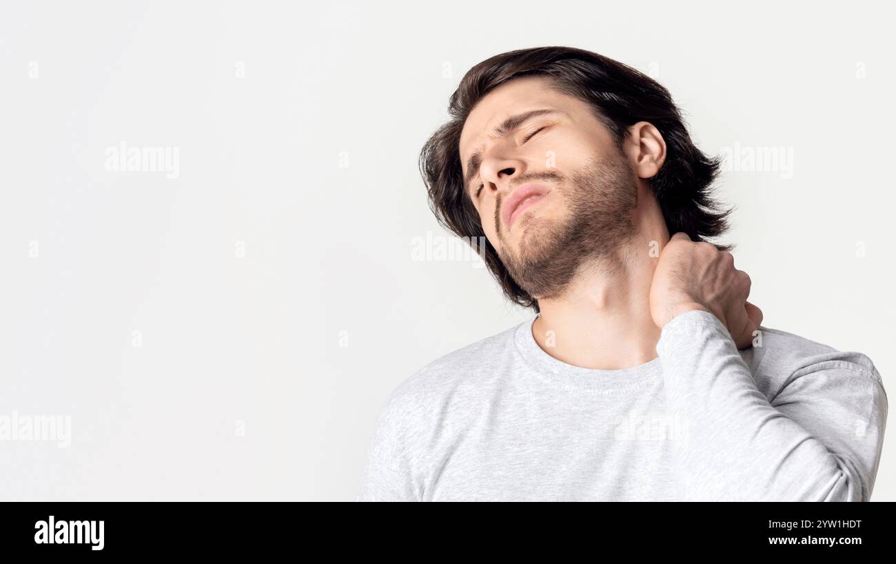 Pain in neck. Guy presses hand to sore spot Stock Photo - Alamy