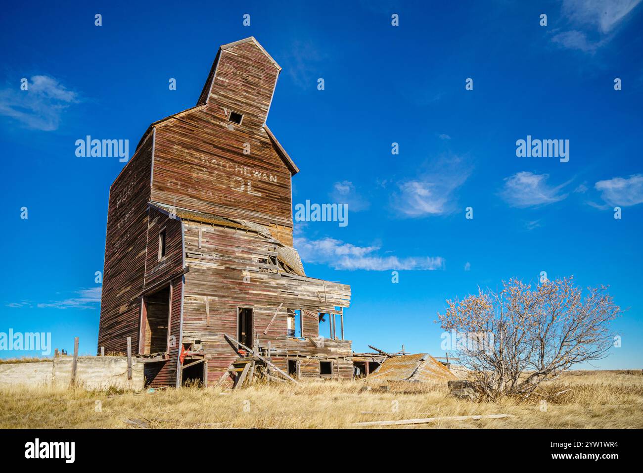 A large, old, abandoned building with a slanted roof. The sky is blue ...