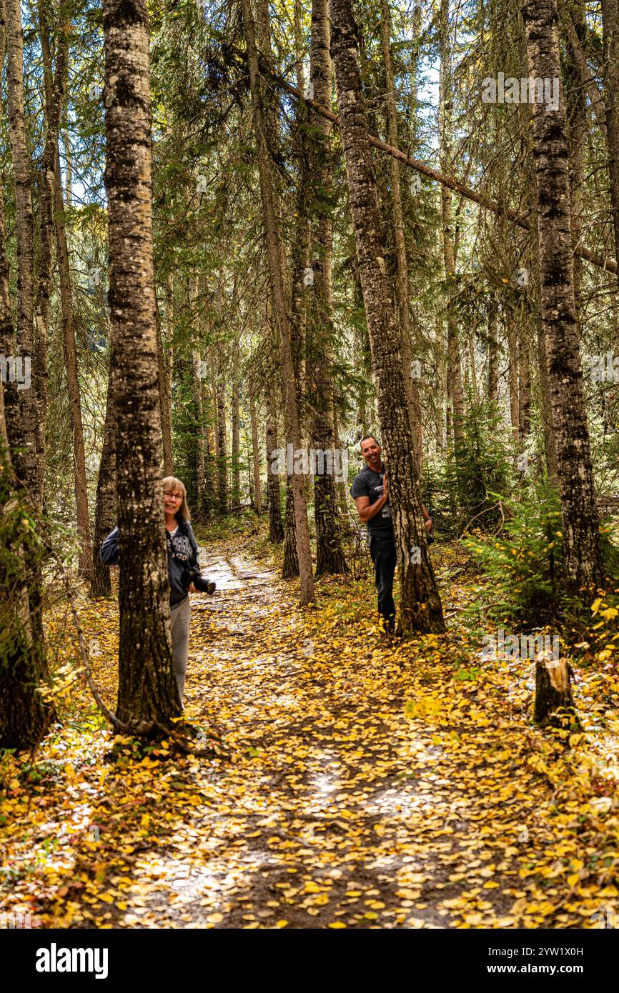 Two people are walking through a forest, one of them is peeking out ...